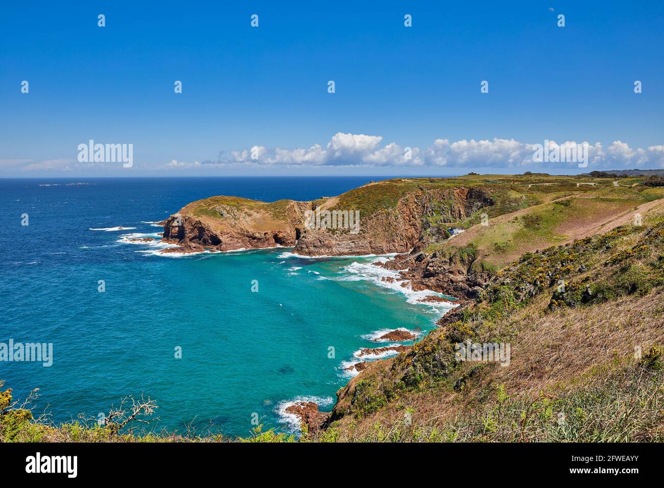 Image of Plemont Bay at high tide with blue sky and the headland ...