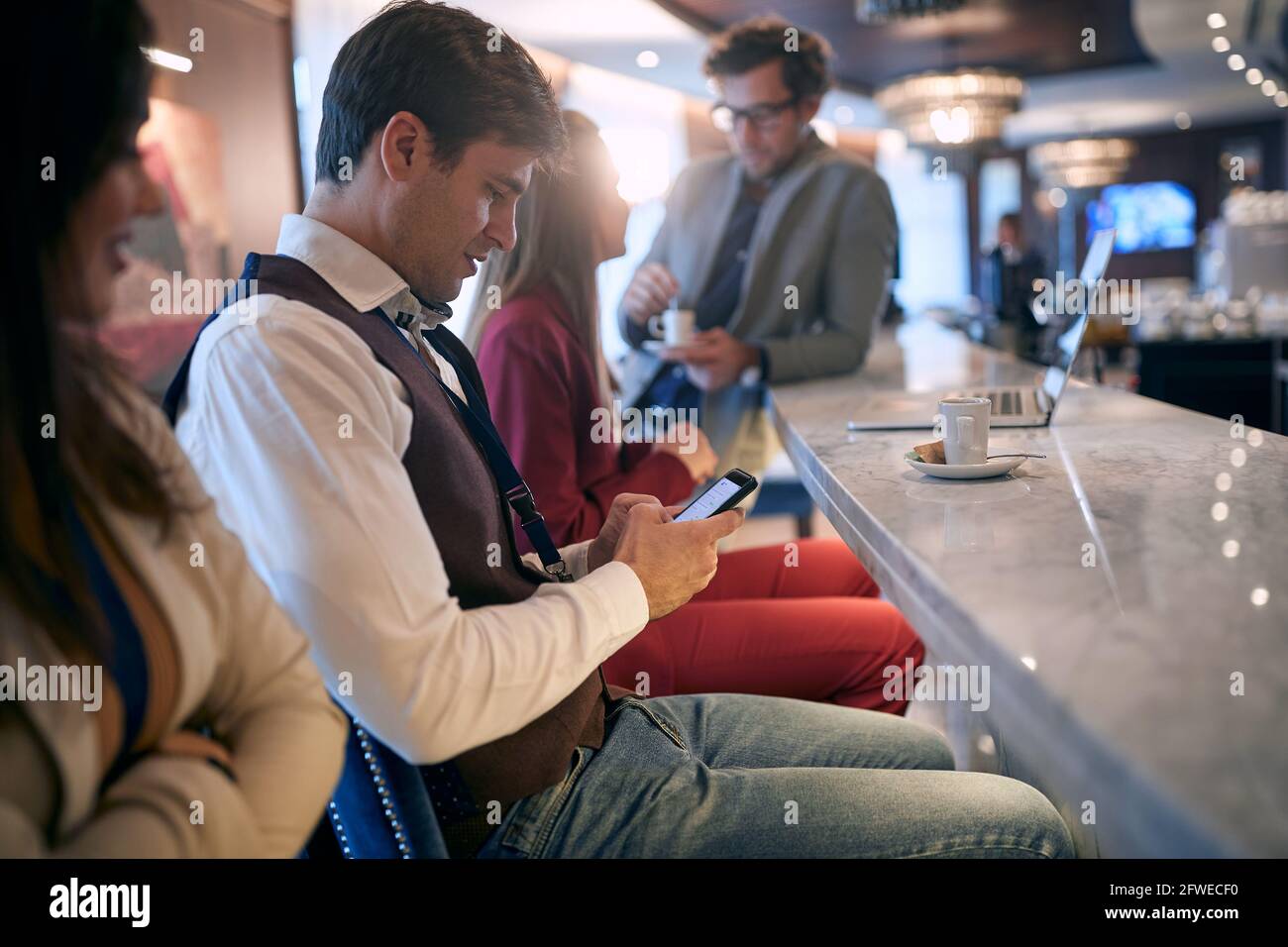young caucasian handsome male sitting at the bar, texting on his cell ...