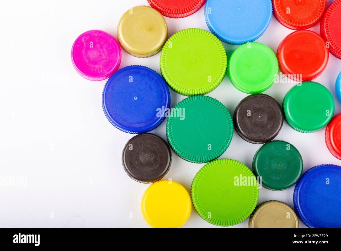 Many multi-colored plastic bottle caps on a white background. Recycling ...