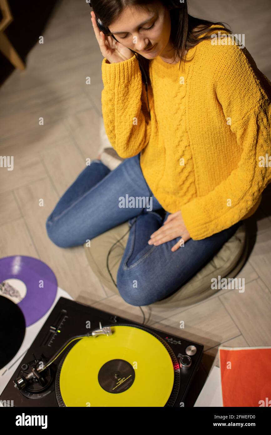 girl sitting on floor enjoys to music with headphones and analog ...