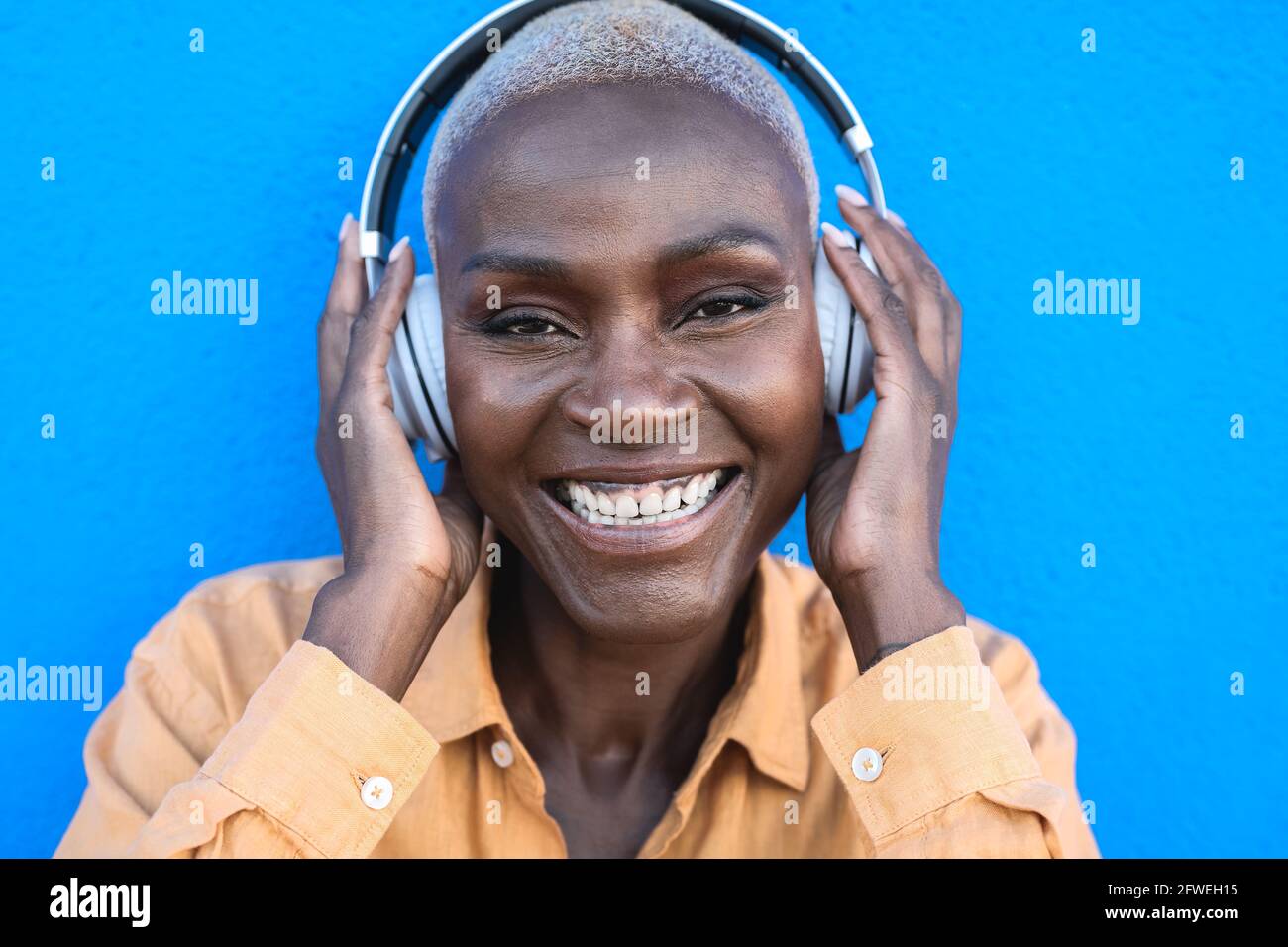 Happy senior African woman having fun listening music with wireless ...