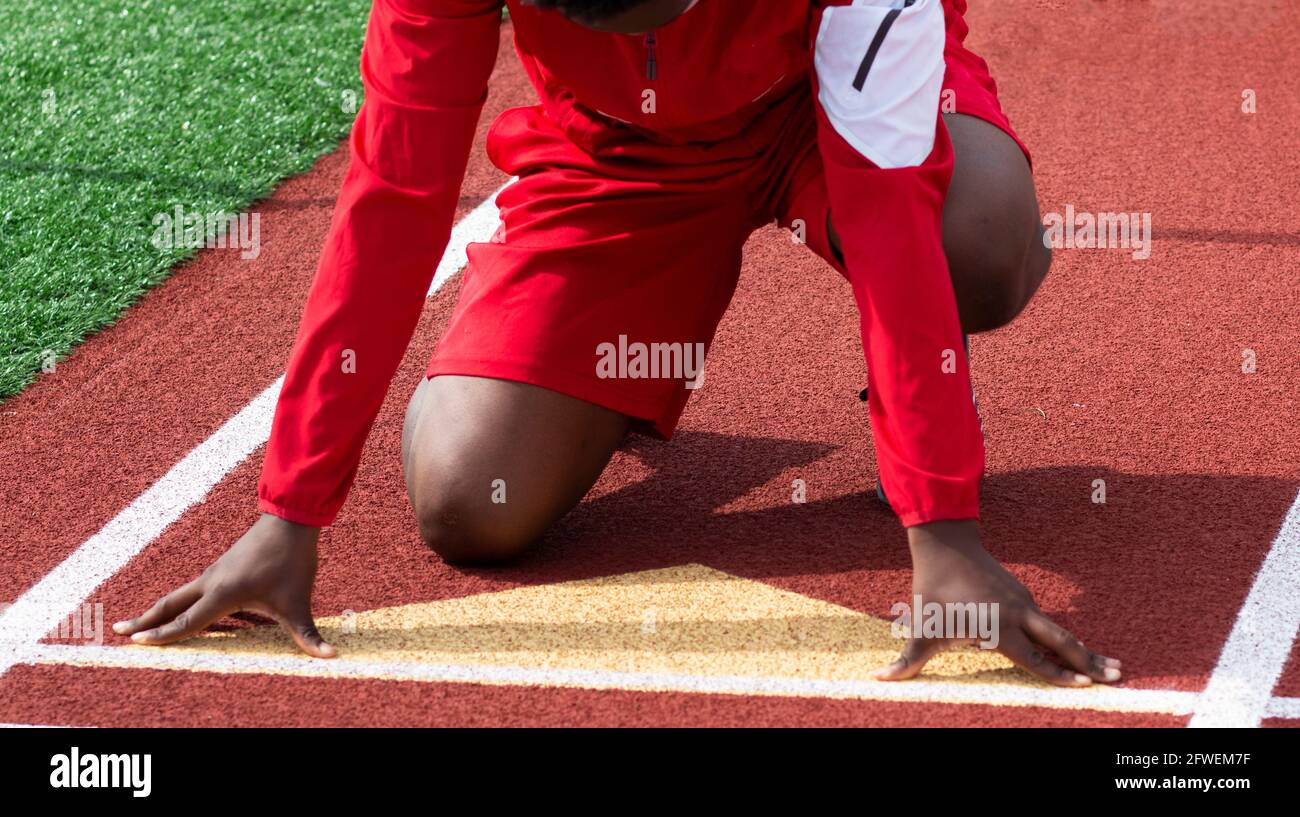 Front view of a high school track sprinter on the starting line ready ...