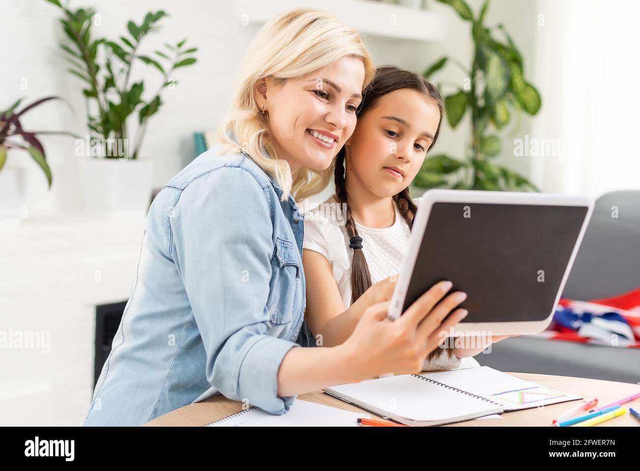 Back to school. Happy child and adult are sitting at desk. Girl doing ...