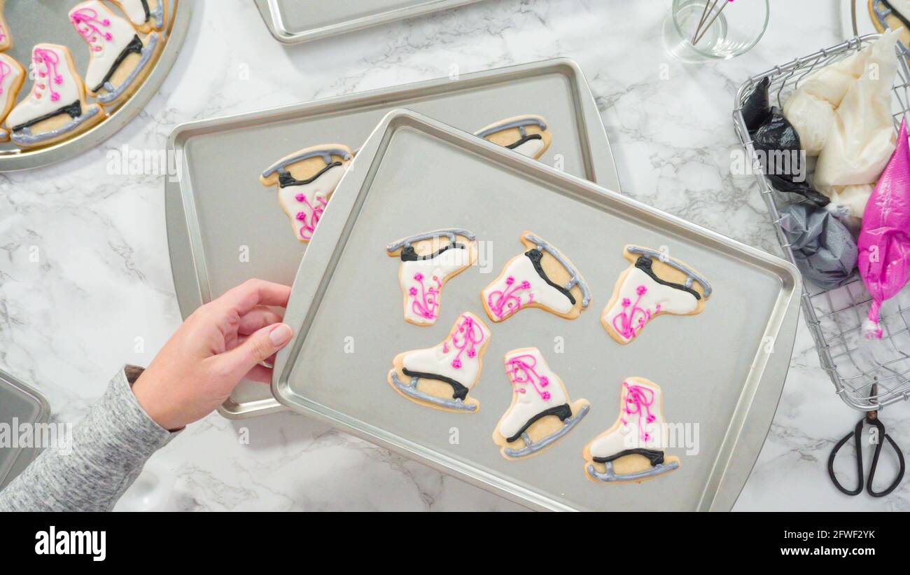 Flat lay. Brushing edible glitter on iced figure skate sugar cookies ...