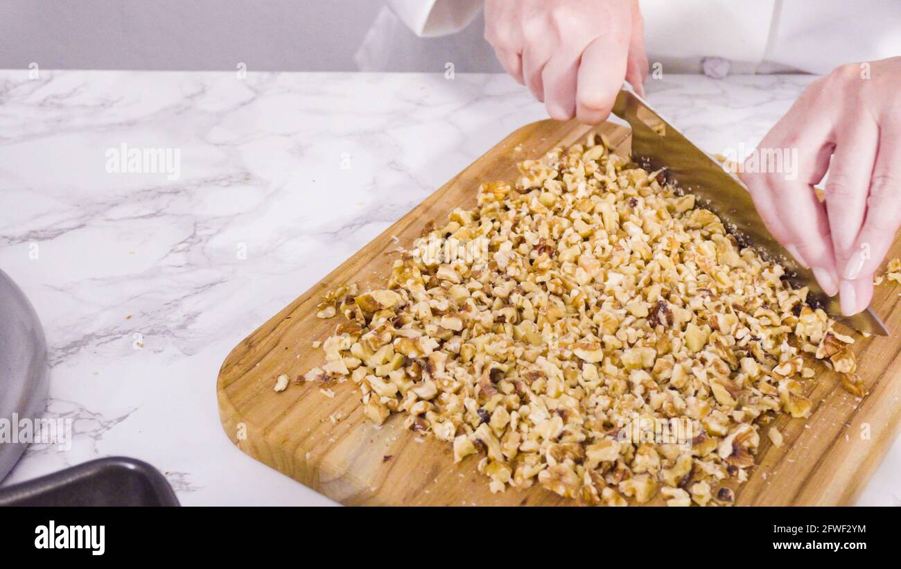 Step by step. Chopping walnuts with kitchen knife on a wood cutting ...