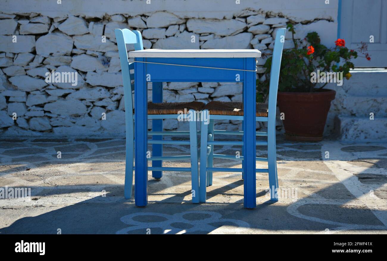Traditional Greek taverna wooden table and wicker chairs against a ...