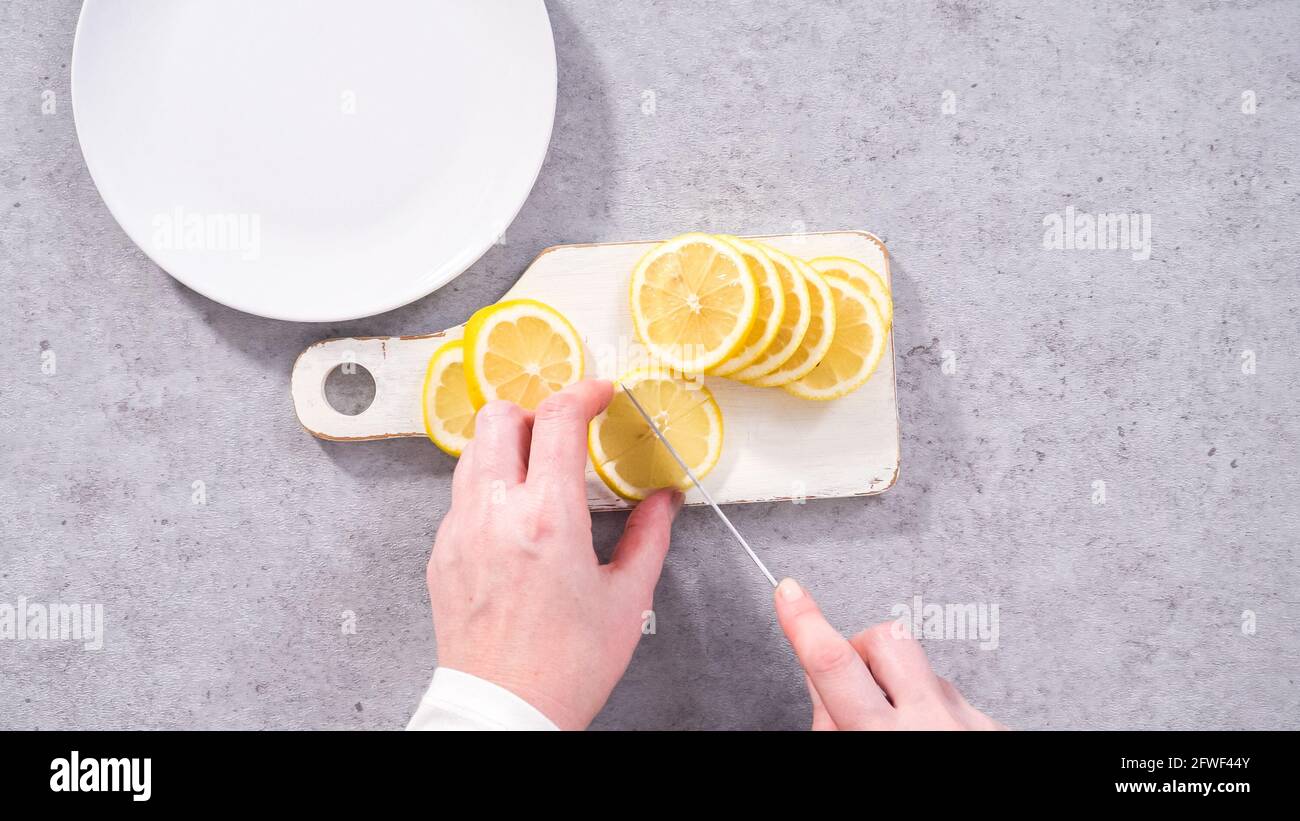 Flat lay. Step by step. Slicing organic lemon wedges on a white plate ...
