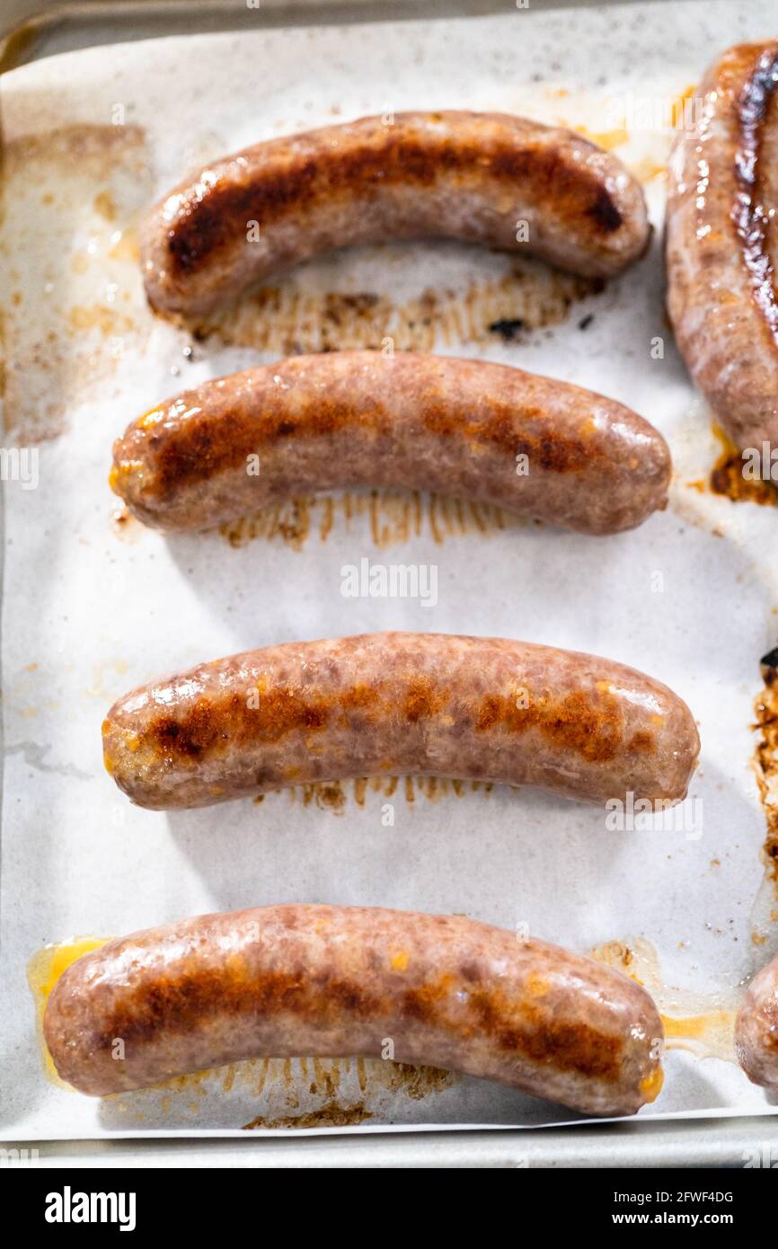 Freshly cooked in oven beer bratwursts on a baking sheet lined with ...