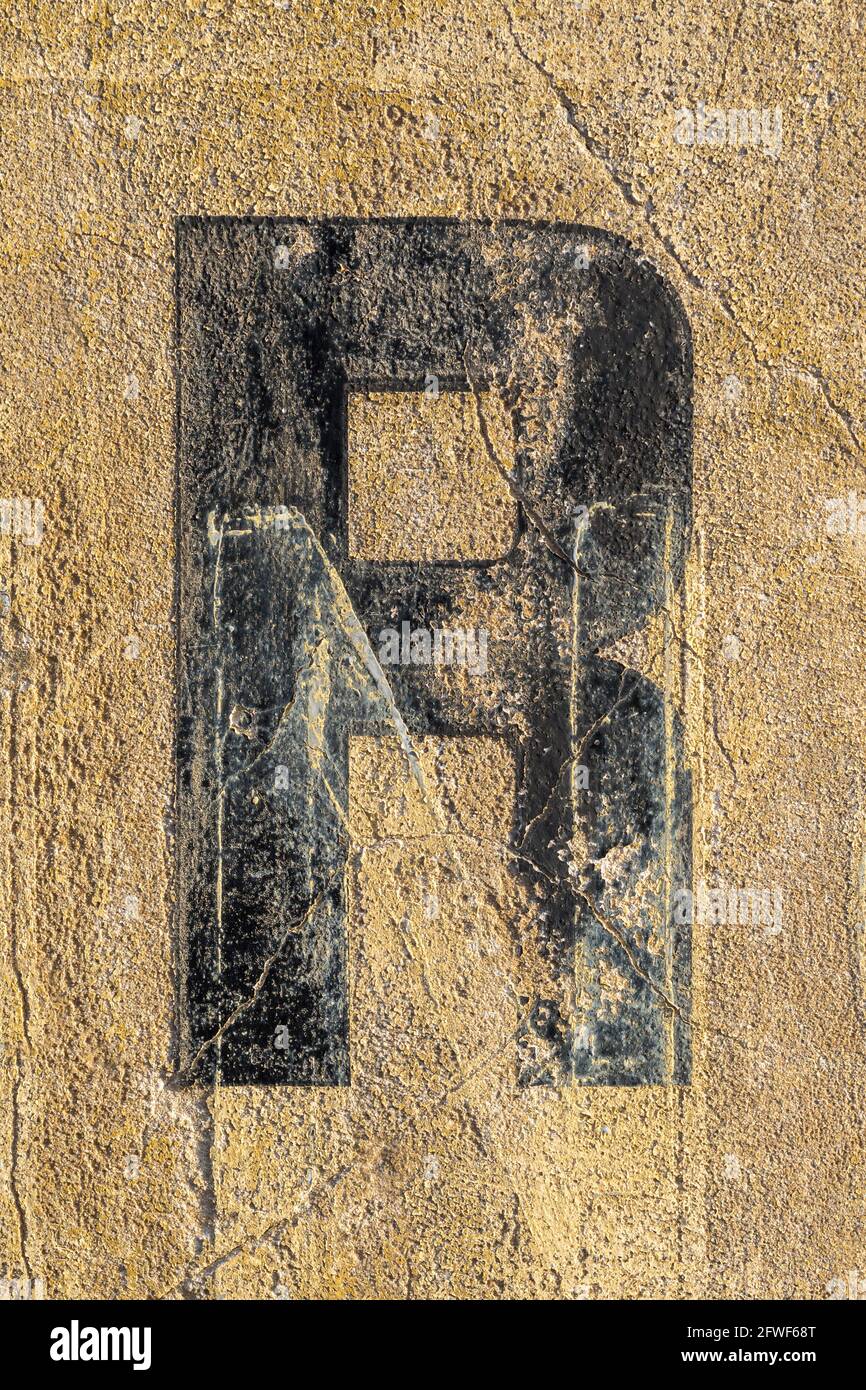 Capital letter R, remains of advertising lettering on a weathered wall ...