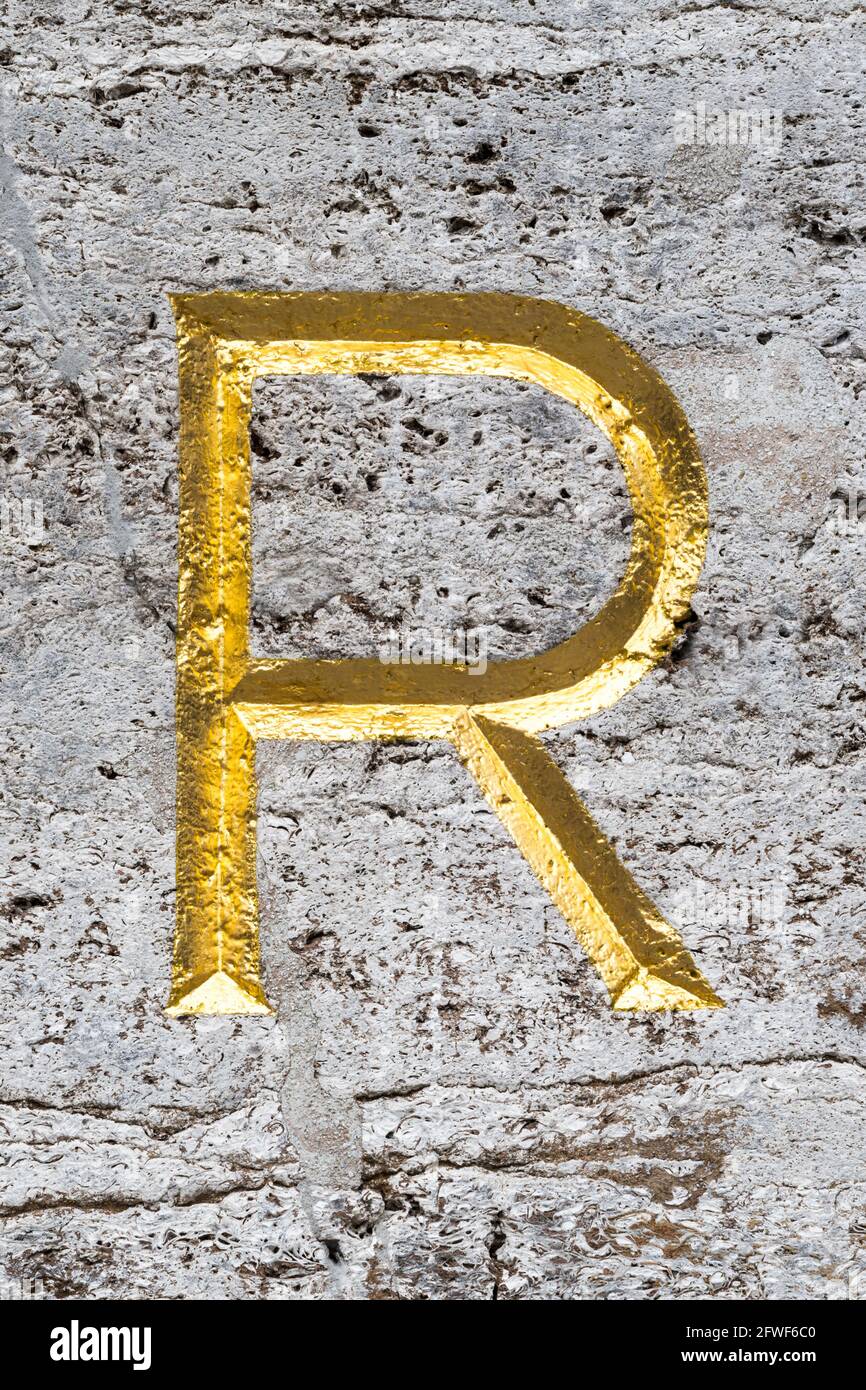 Golden letter R engraved in natural stone Stock Photo - Alamy