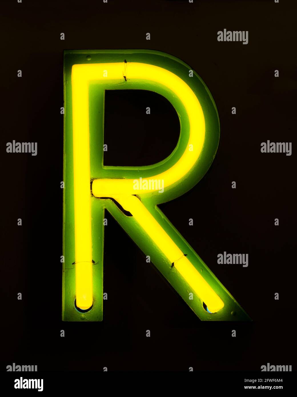 Yellow neon letter R glowing in the dark Stock Photo - Alamy