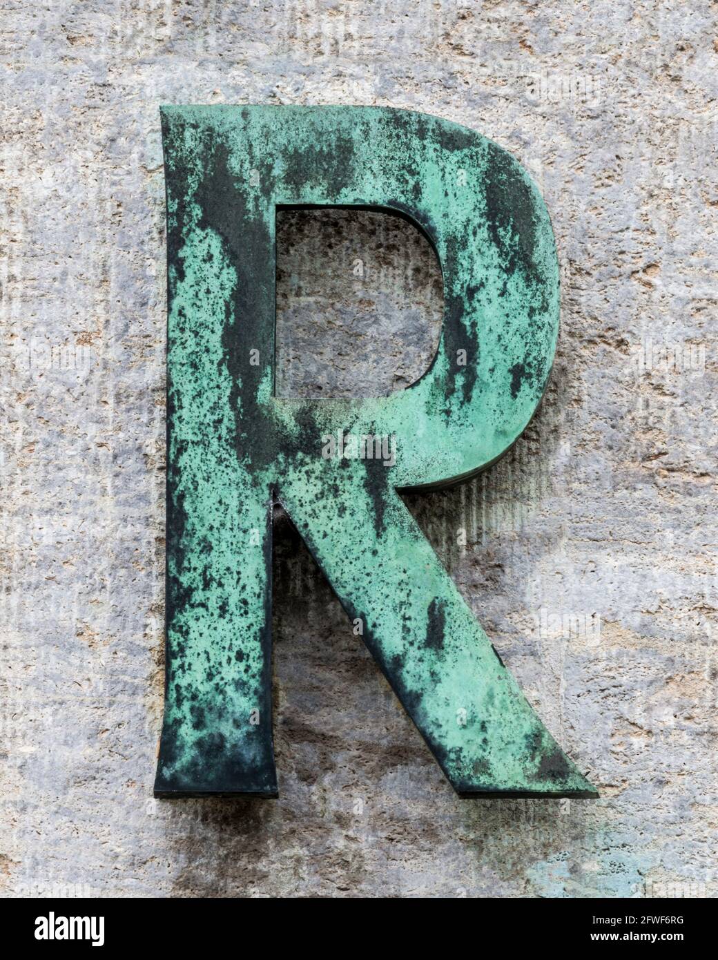 Metal letter R covered with verdigris on a natural stone wall Stock ...