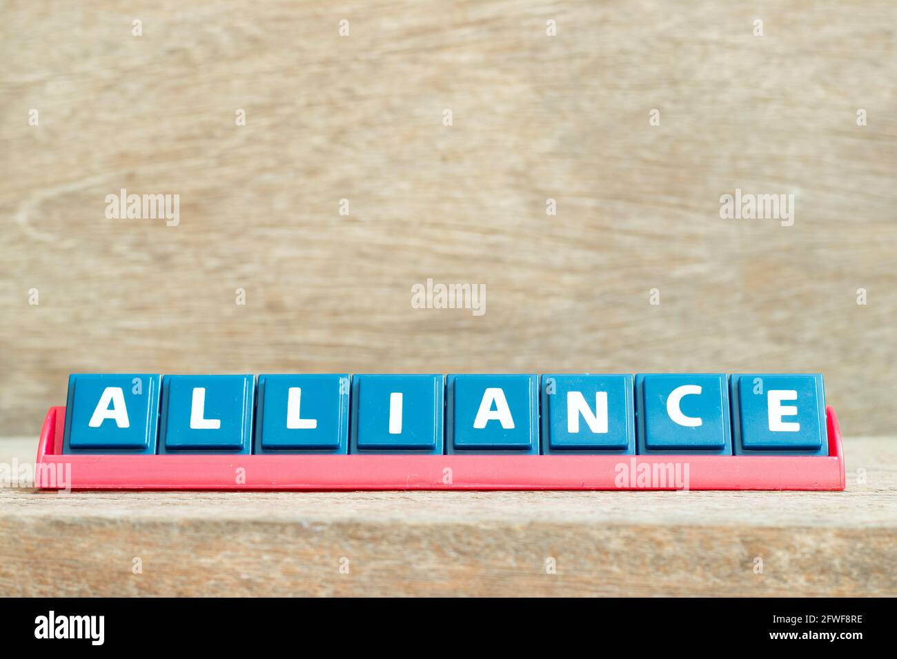 Tile alphabet letter with word alliance in red color rack on wood ...