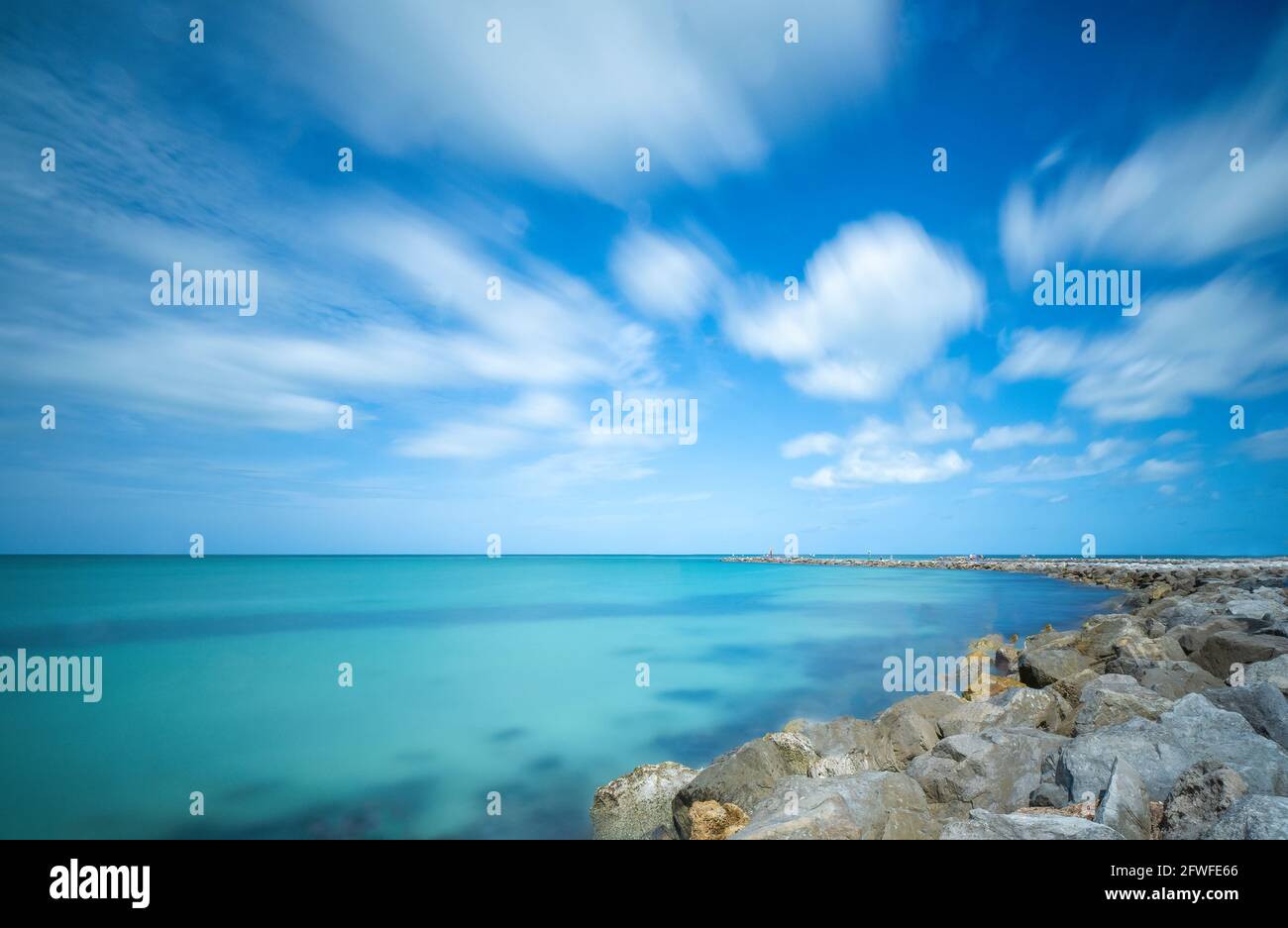 Blue sky with moving white clouds over the blue green colored Gulf of ...