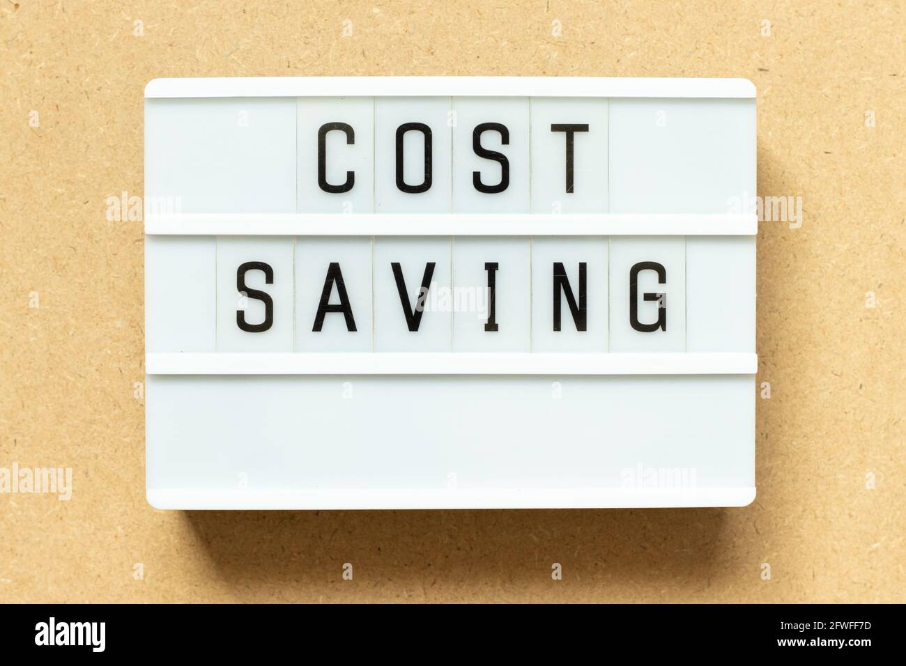 Lightbox with word cost saving on wood background Stock Photo - Alamy