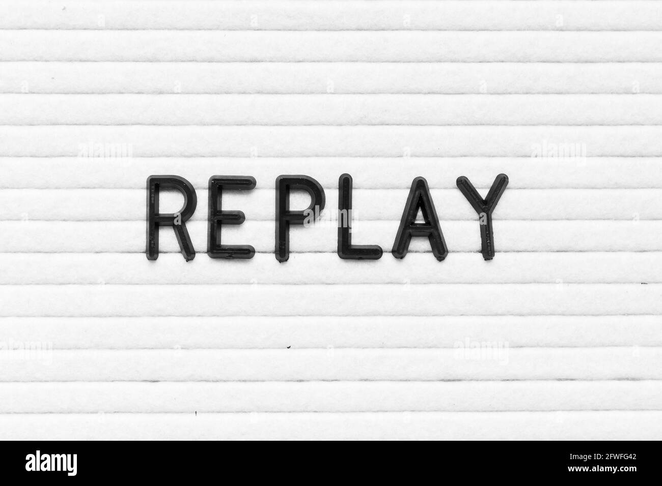 Black color letter in word replay on white felt board background Stock ...