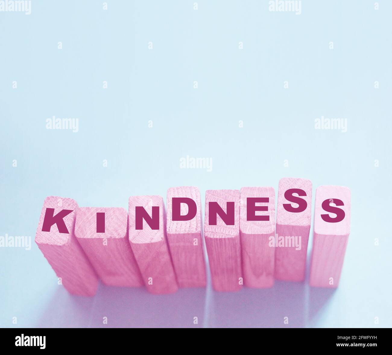 KINDNESS word made with wooden building blocks on neon aquamarine ...