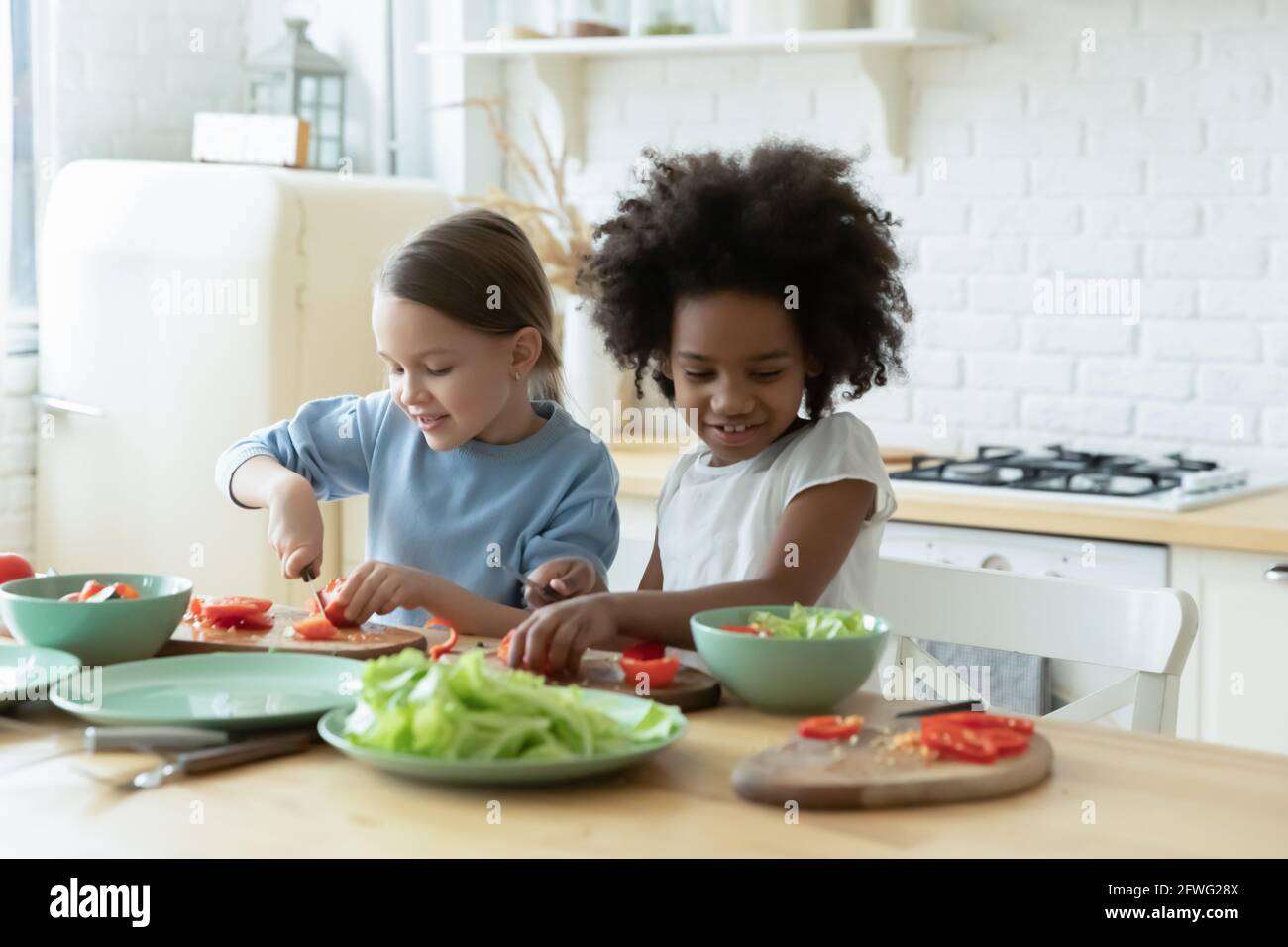 Happy multiethnic small girls cook in kitchen Stock Photo - Alamy