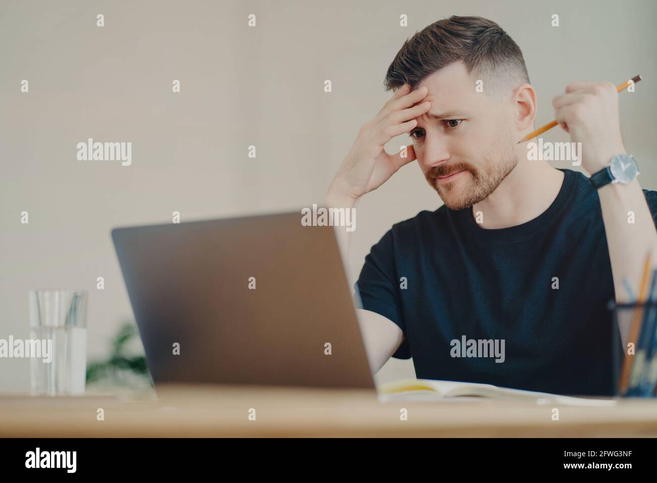 Stressed male office worker looking at laptop with worried face ...