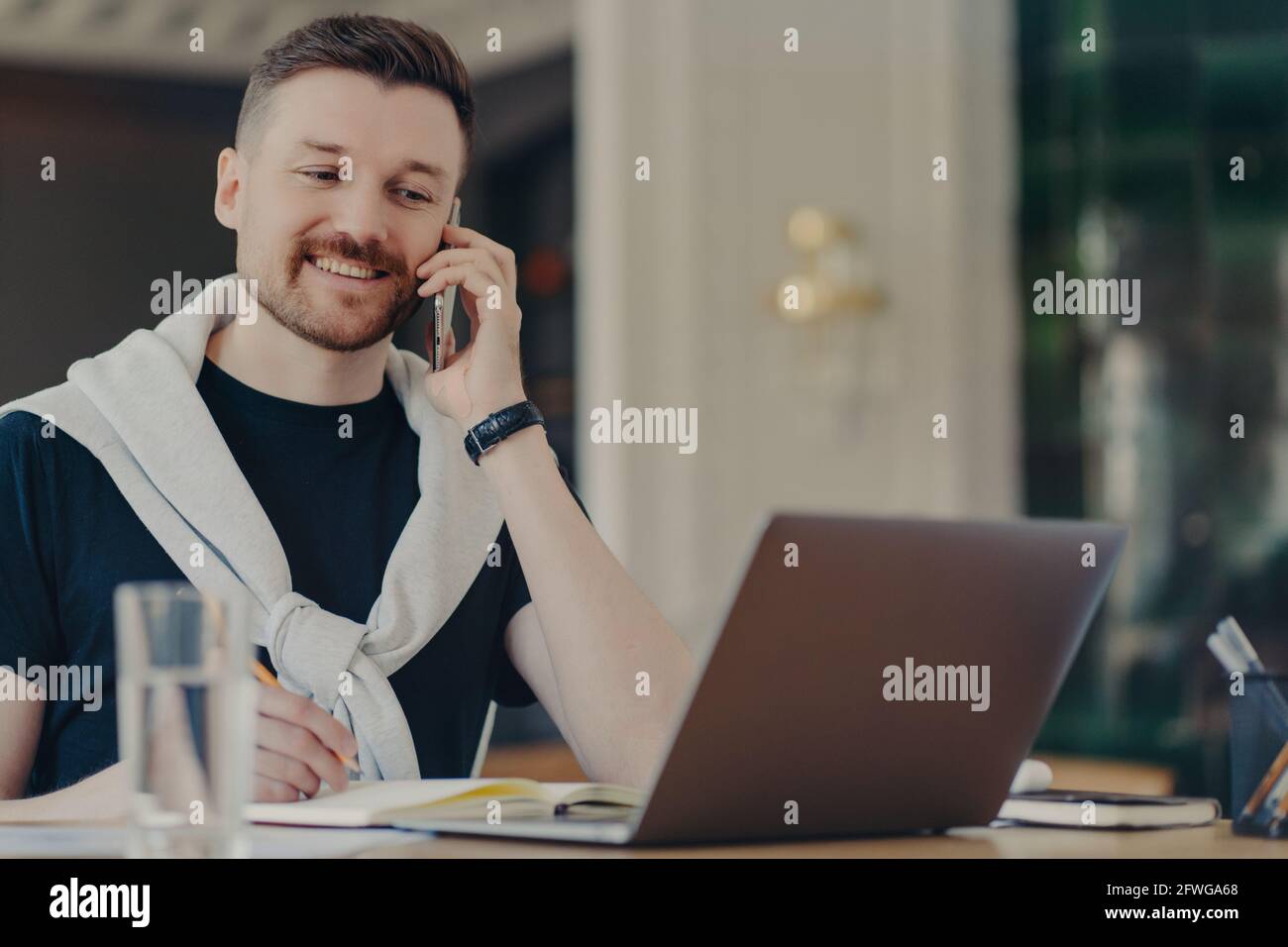 Happy businessman talking on mobile phone while working from home Stock ...