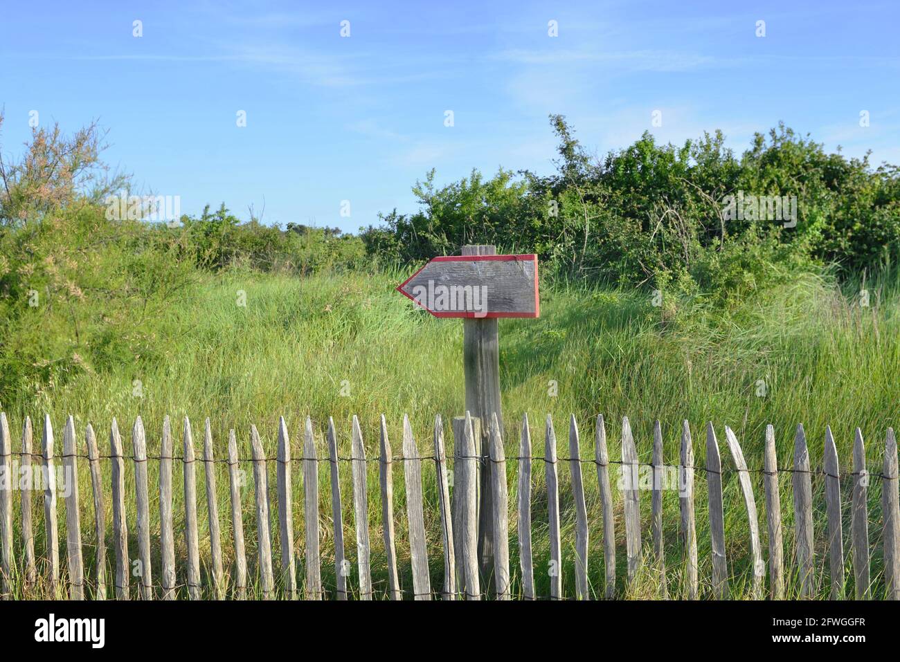 natural fence in front of a meadow with a sign in french nature reserve ...