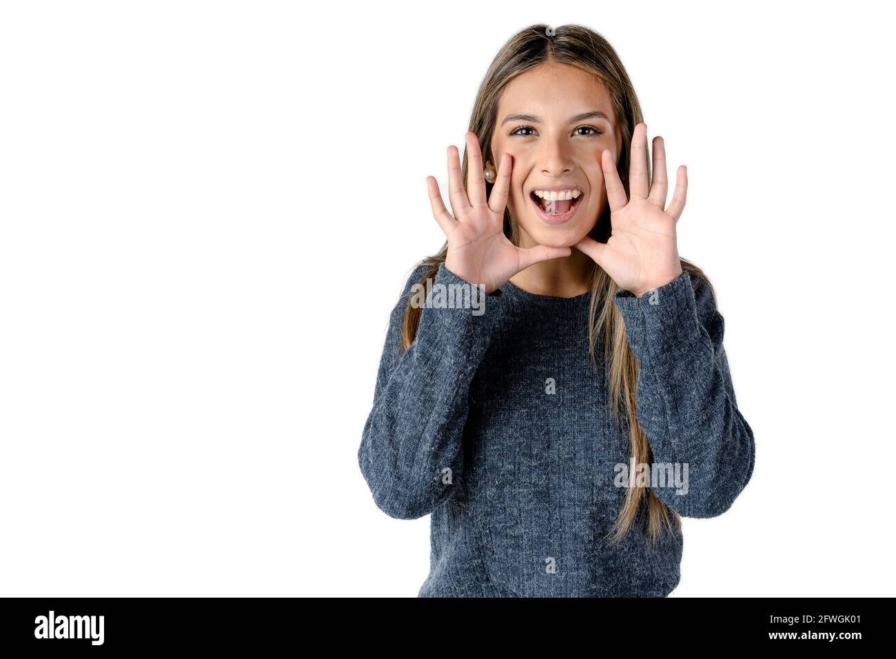 Attractive Latin woman screaming with her hands at the sides of her mouth on a pure white ...