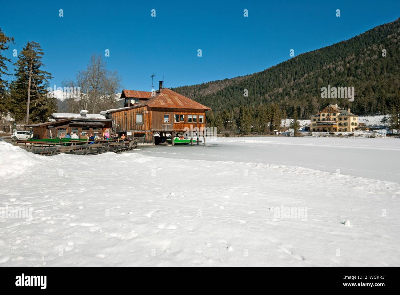 Dobbiaco lake in winter with bar-restaurant on stilts and historic ...