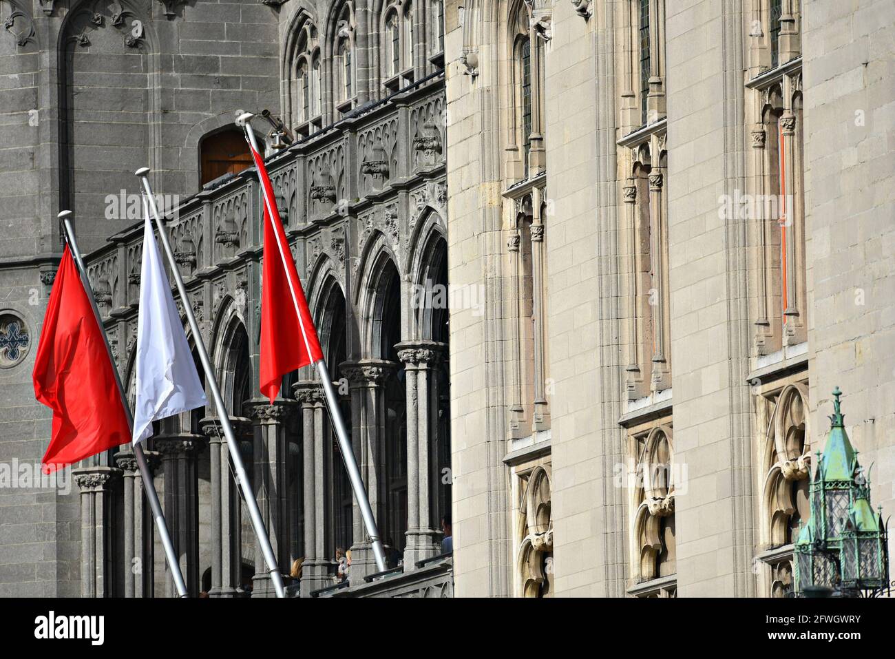 Gothic style facade with stone arches and Flemish flags of the ...