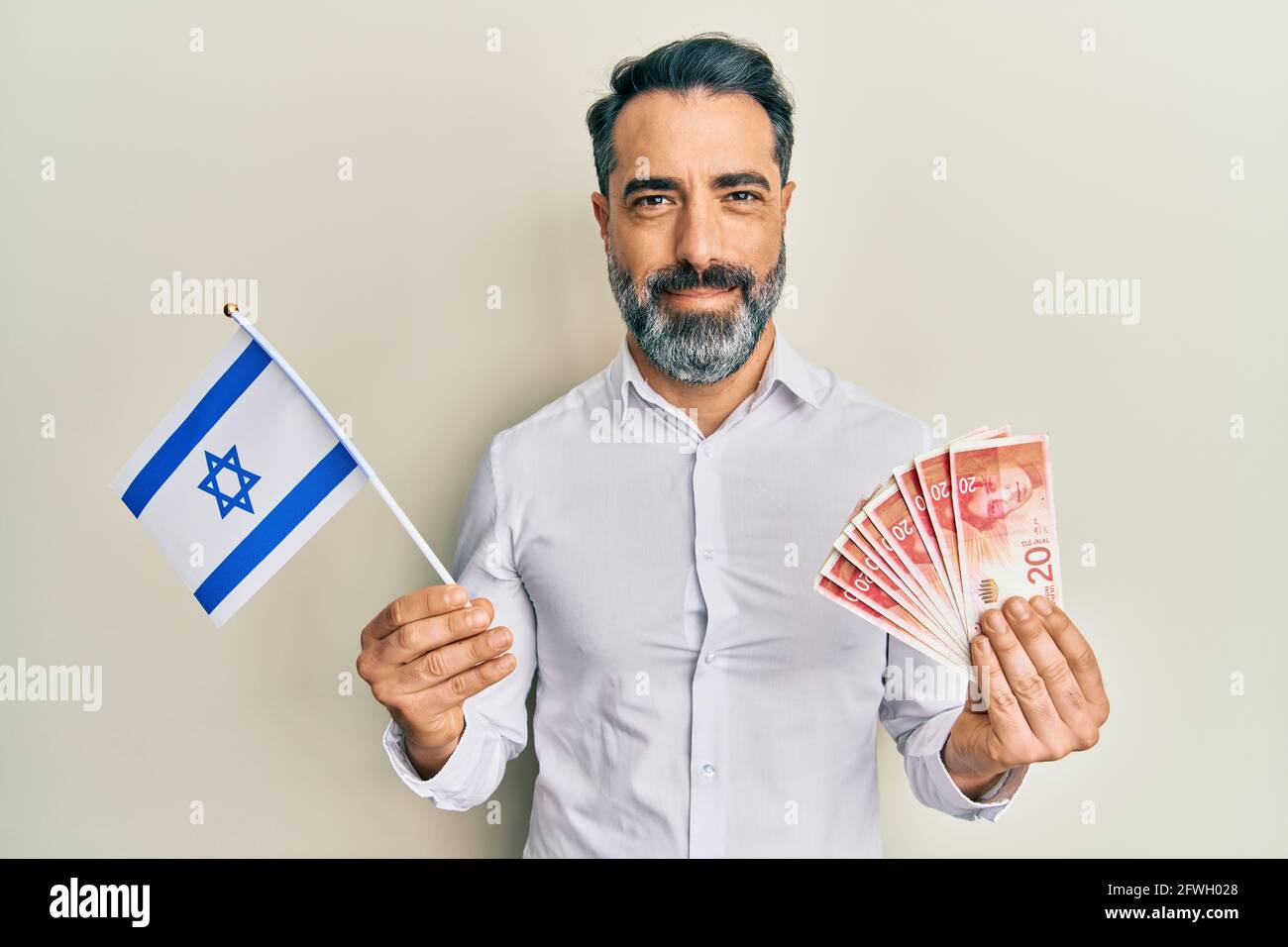 Middle age man with beard and grey hair holding israel flag and shekels ...