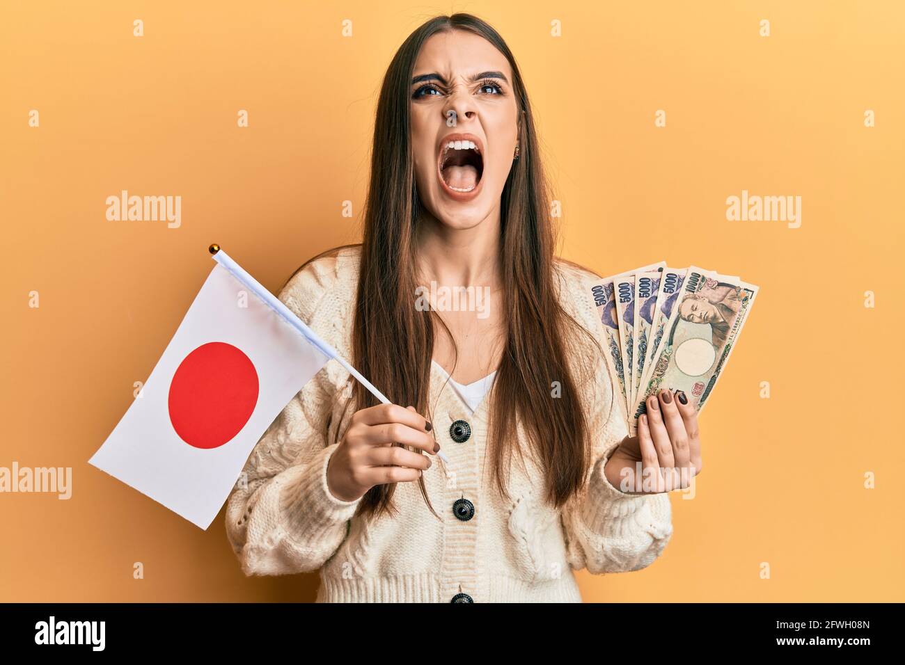 Beautiful brunette young woman holding japan flag and yen banknotes ...