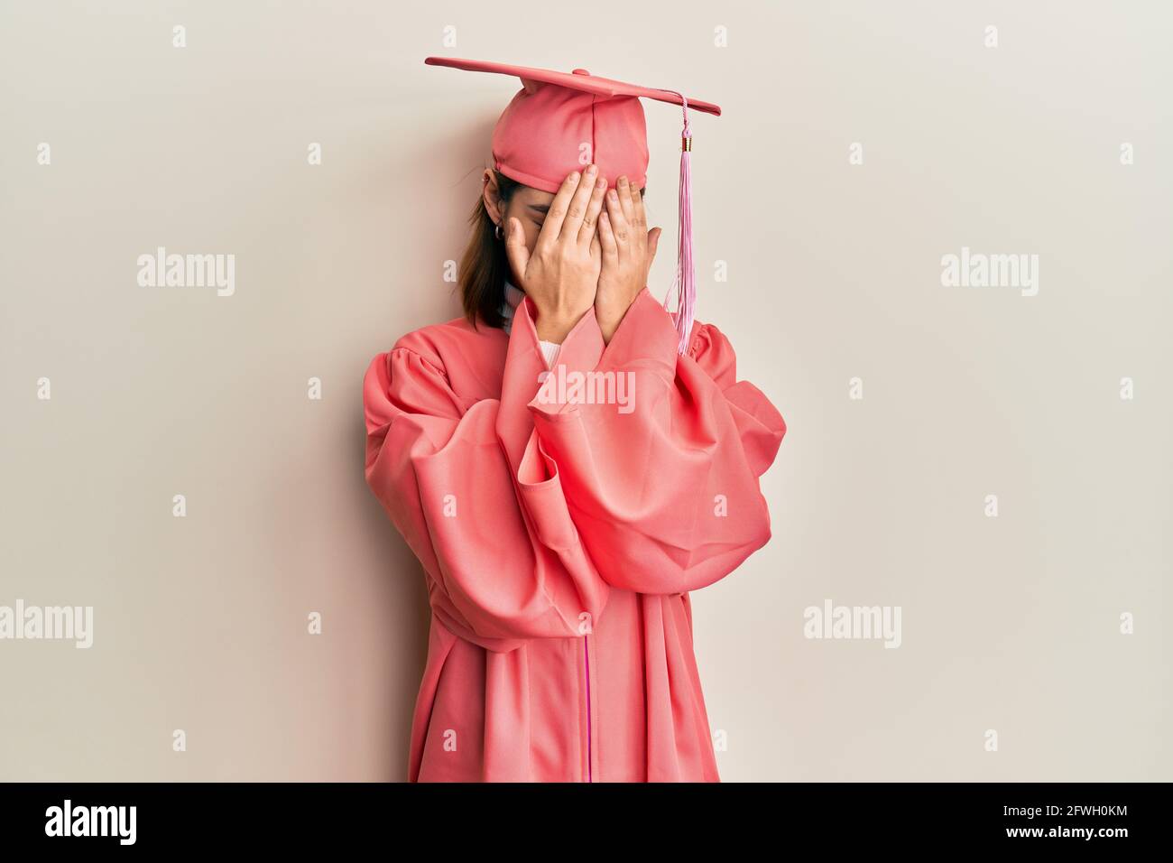 Young caucasian woman wearing graduation cap and ceremony robe with sad ...