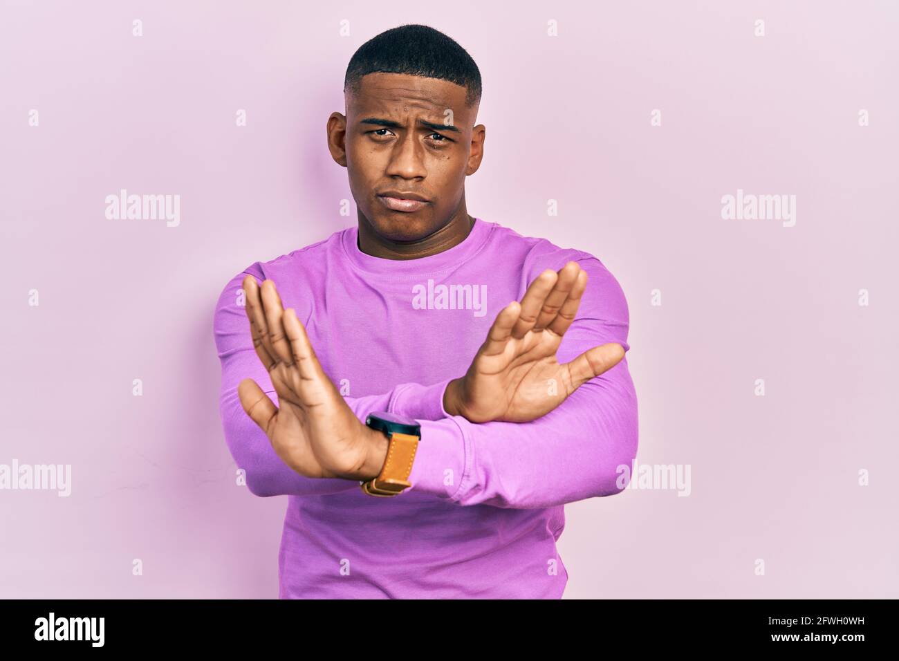 Young black man wearing casual pink sweater rejection expression ...