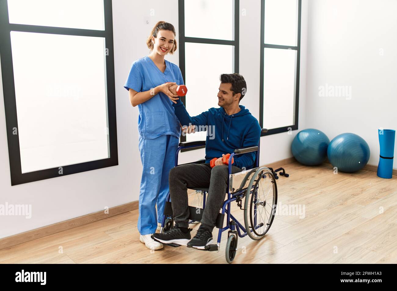 Young disabled man sitting on wheelchair making mobility exercise using ...