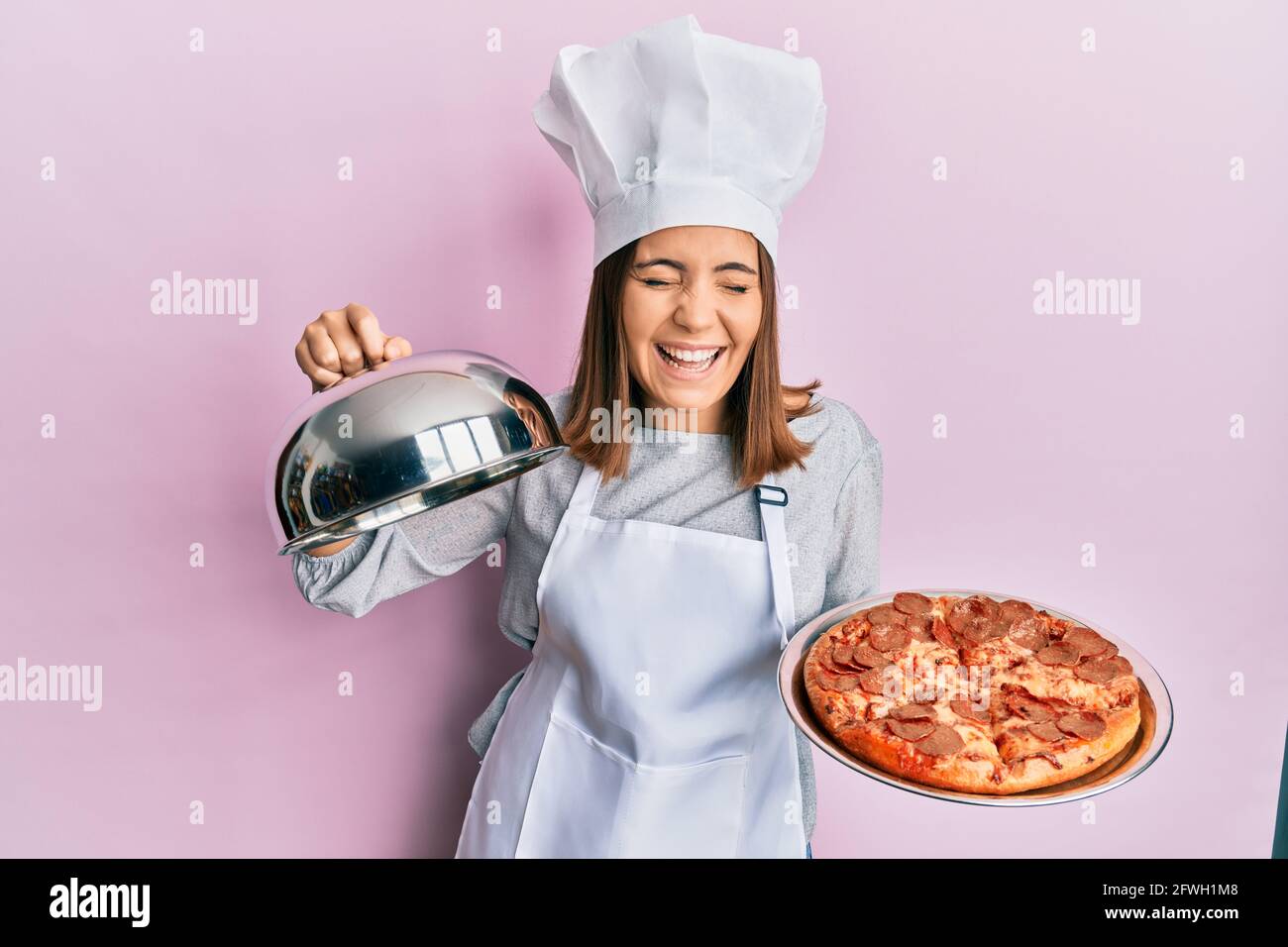 Young beautiful woman professional cook holding italian pizza smiling ...