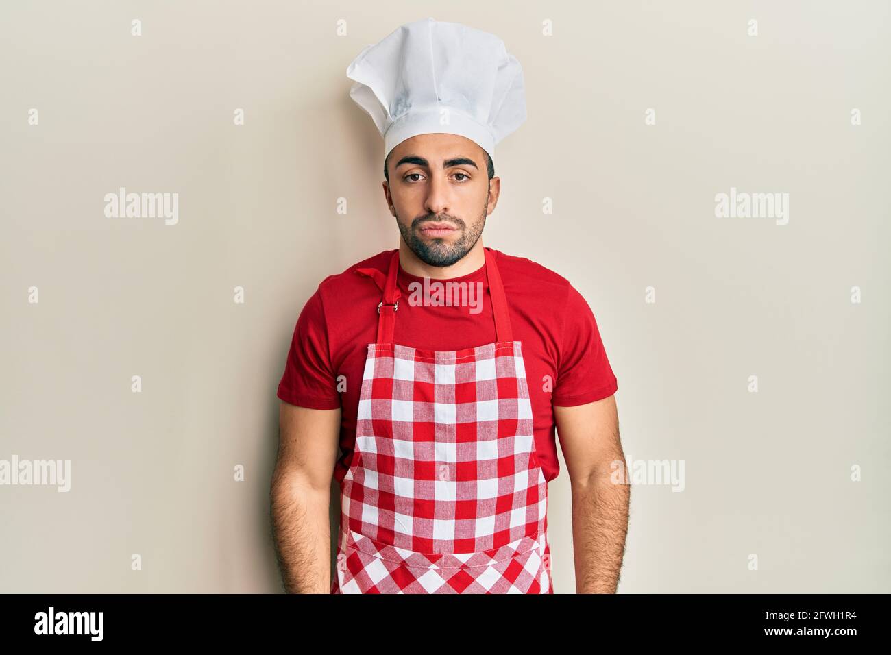 Young hispanic man wearing baker uniform depressed and worry for ...