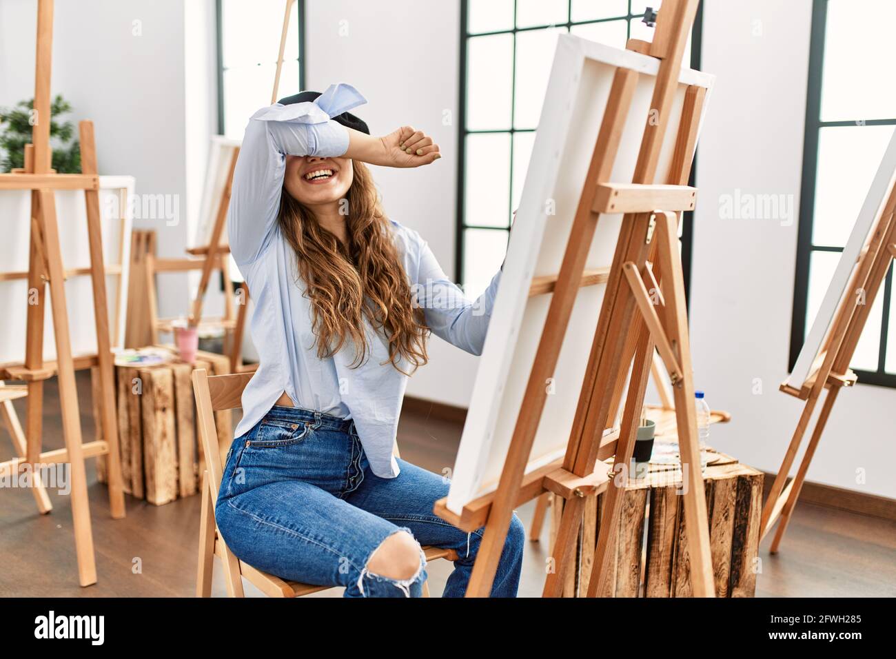 Young hispanic artist woman painting on canvas at art studio smiling ...