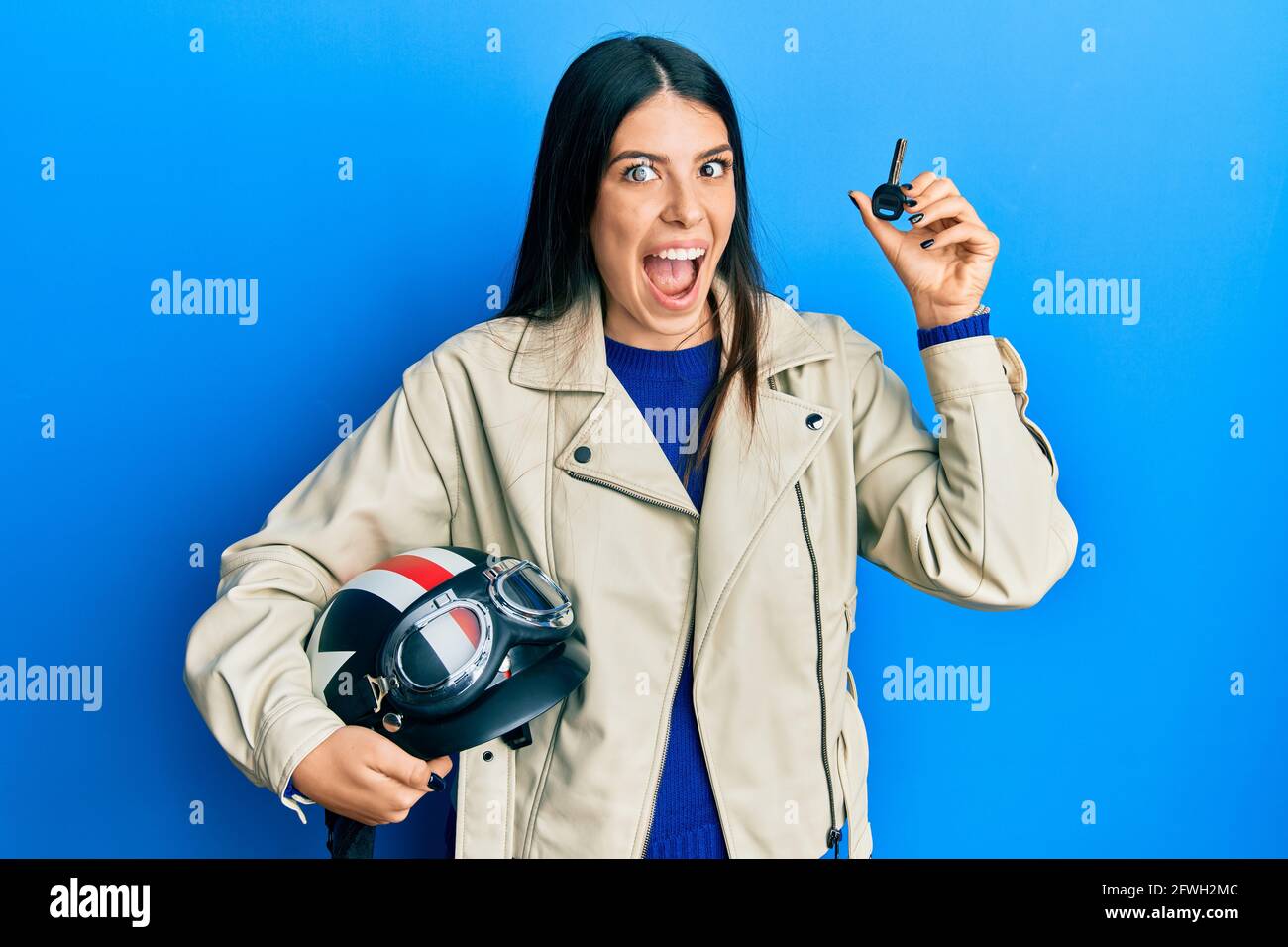Young hispanic woman holding motorcycle helmet and key celebrating ...