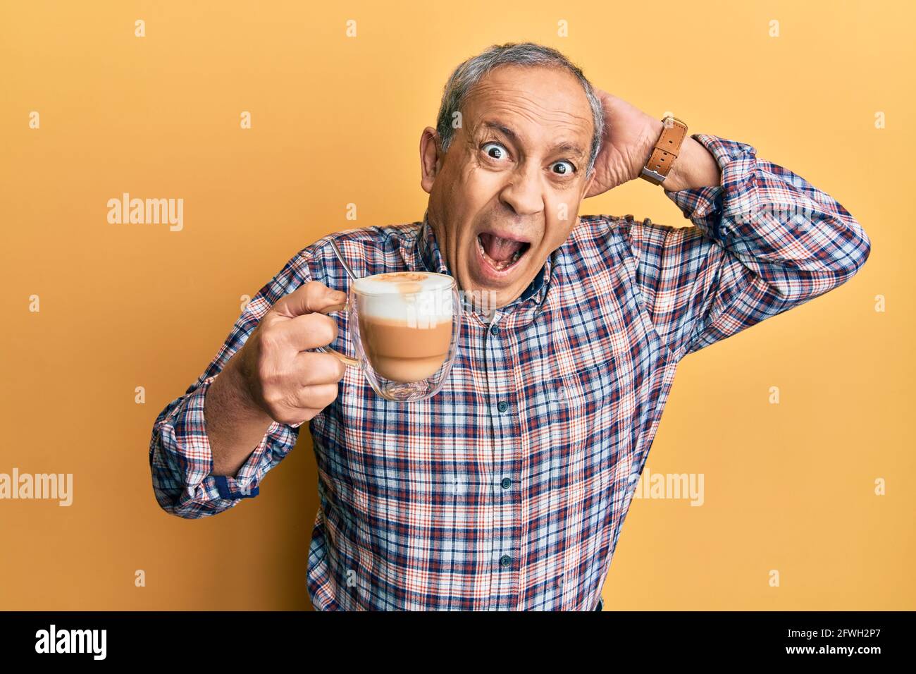 Handsome senior man with grey hair drinking a cup coffee crazy and ...