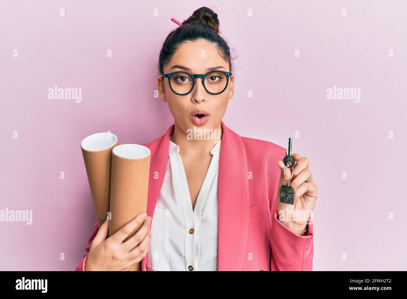 Beautiful middle eastern woman holding paper blueprints and house keys ...