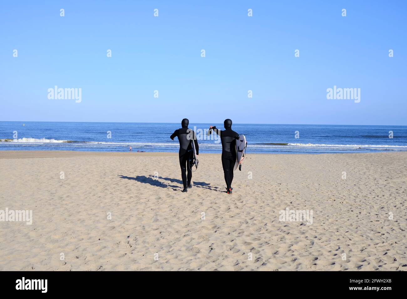 Two surfers walking across the beach to the sea to find the best ...