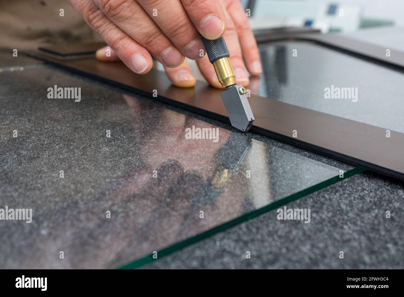 The glazier cuts the glass with a hand-held cutting tool. Handicraft ...