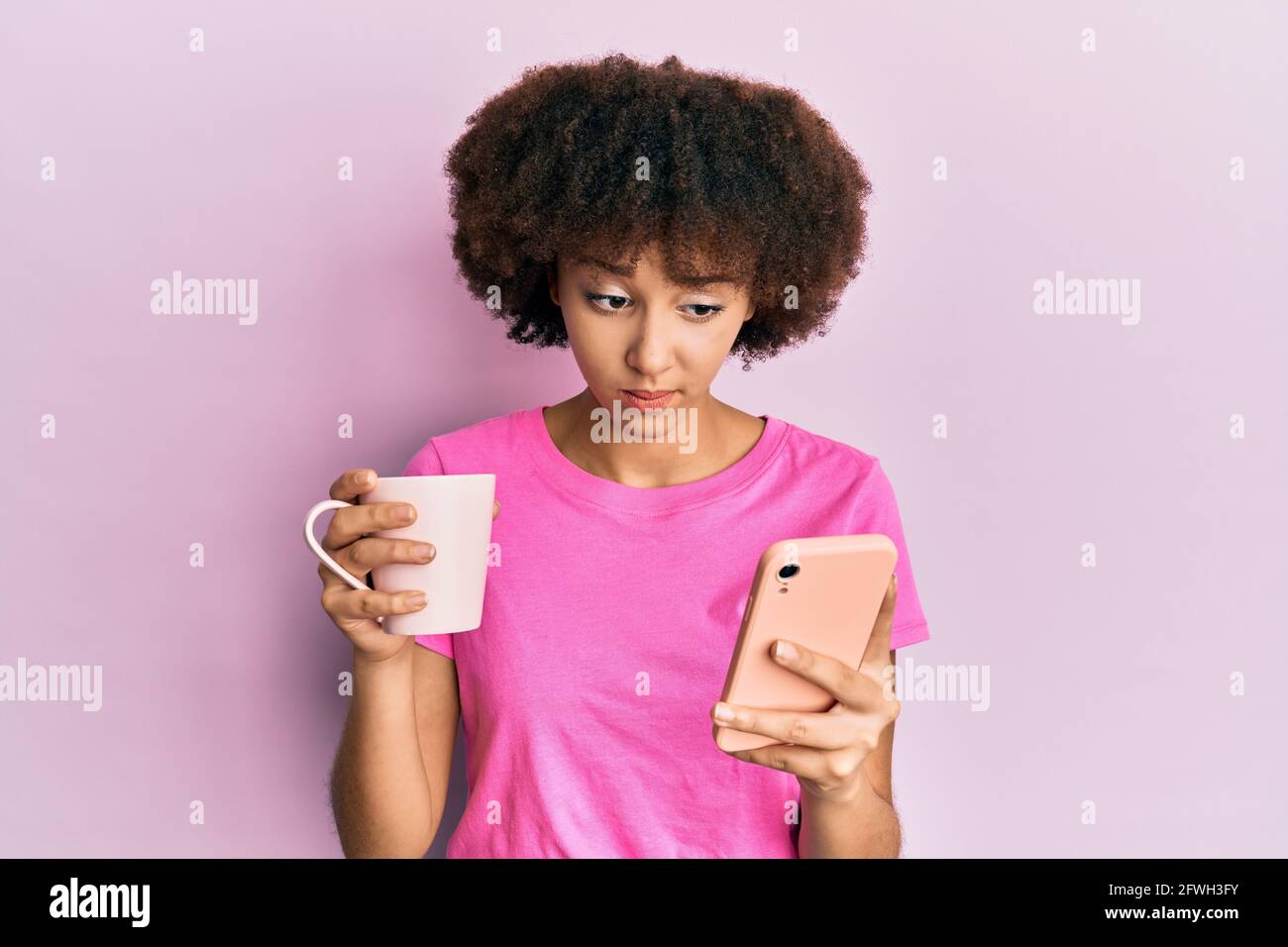 Young hispanic girl using smartphone and drinking a cup of coffee ...