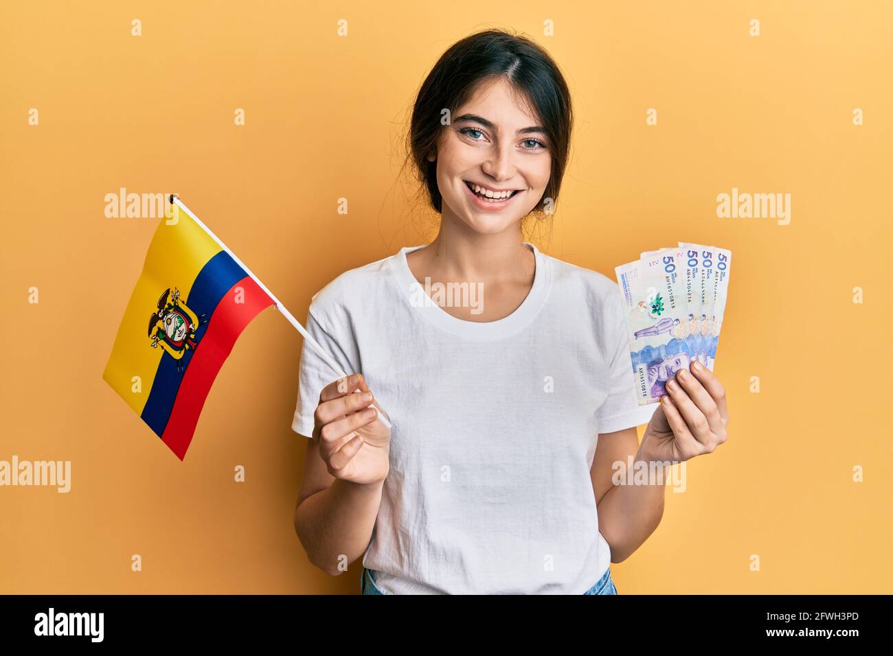 Young caucasian woman holding colombia flag and colombian pesos ...