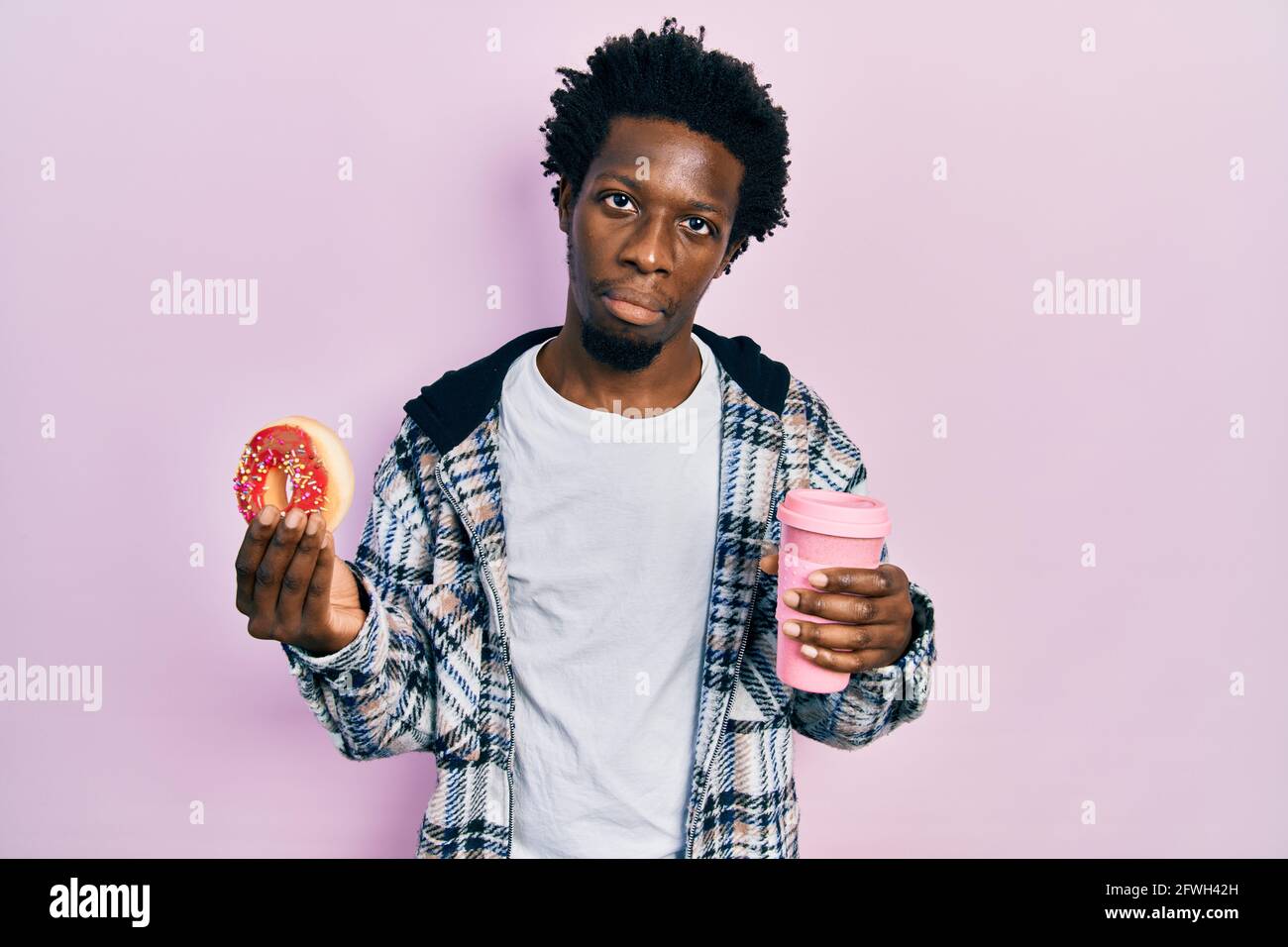 Young african american man eating doughnut and drinking coffee ...