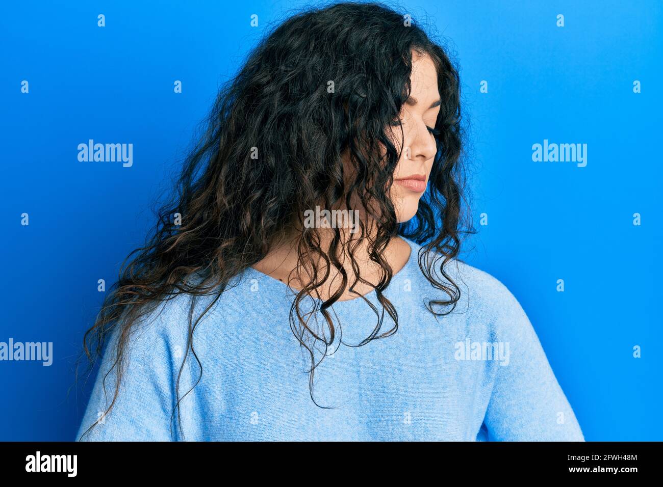 Young brunette woman with curly hair wearing casual clothes with hand ...