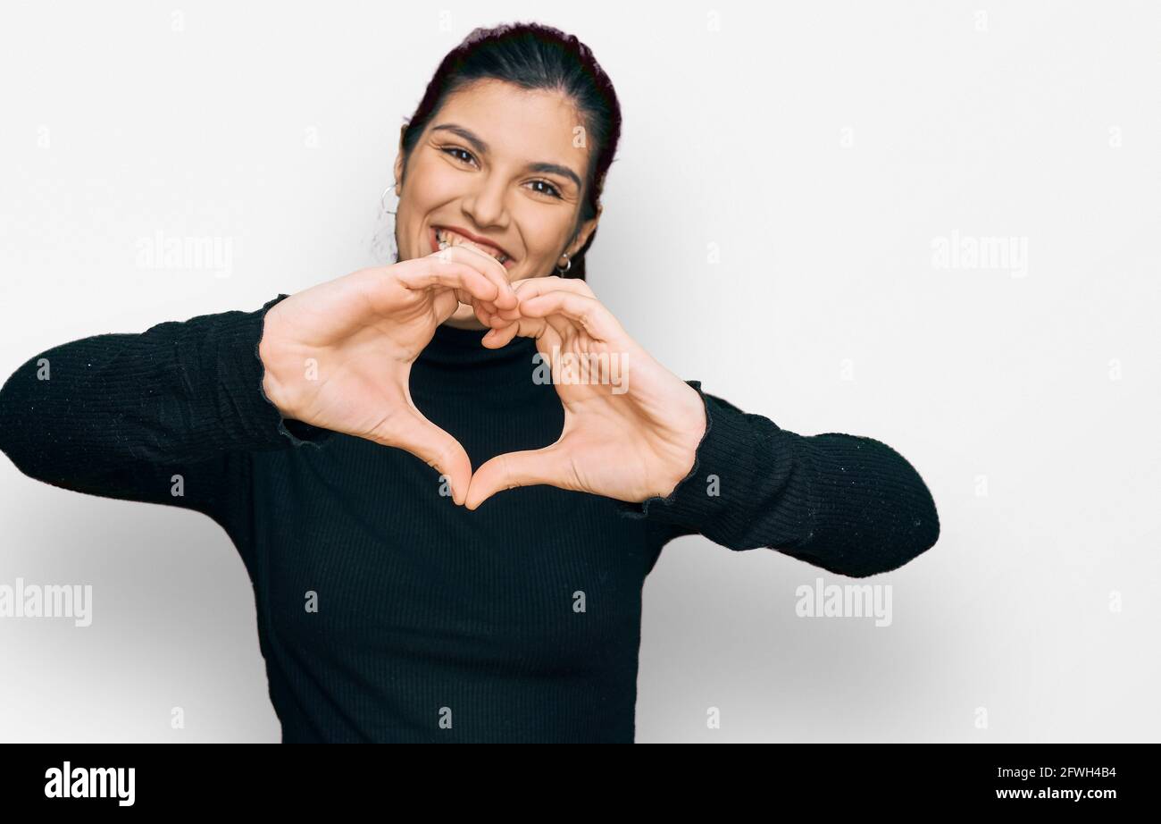 Young hispanic woman wearing casual clothes smiling in love doing heart ...