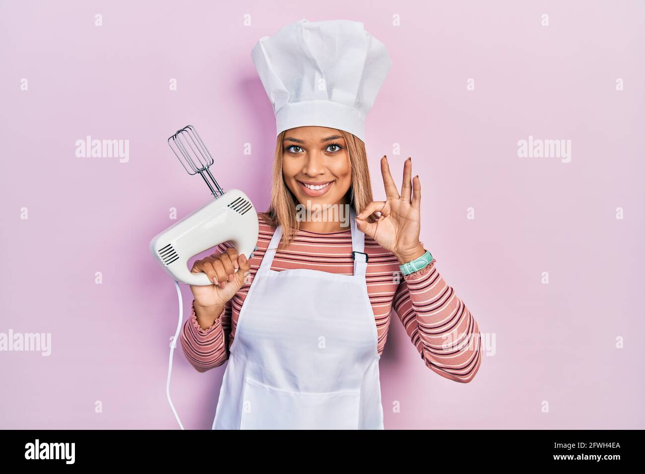 Beautiful hispanic woman holding pastry blender electric mixer smiling ...