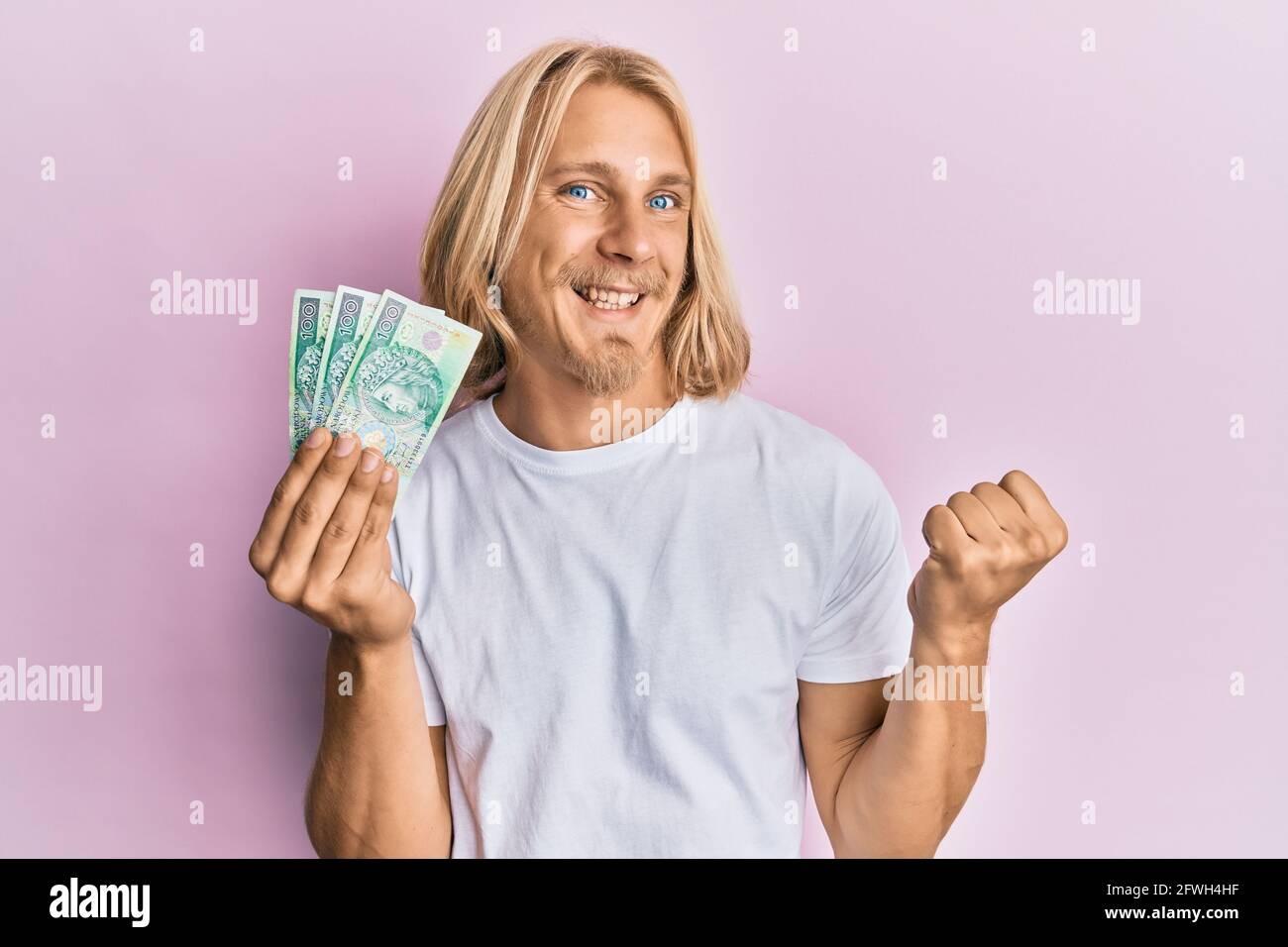 Caucasian young man with long hair holding 100 polish zloty banknotes ...