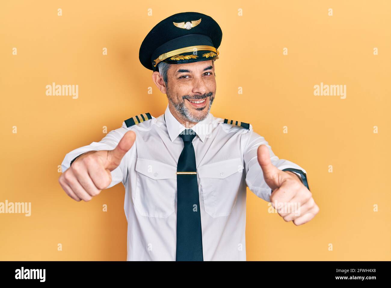 Handsome middle age man with grey hair wearing airplane pilot uniform ...