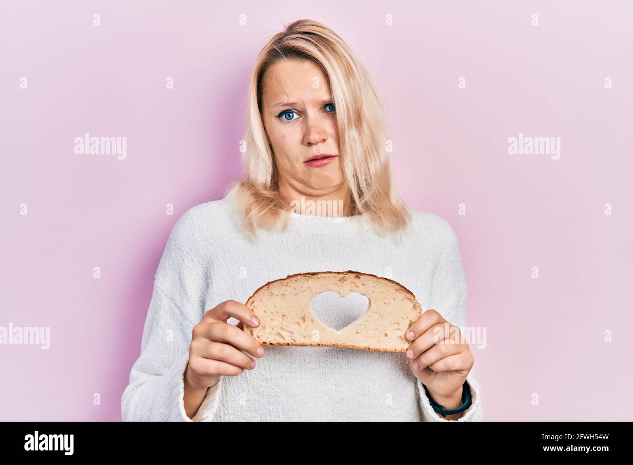 Beautiful caucasian blonde woman holding bread loaf with heart shape ...